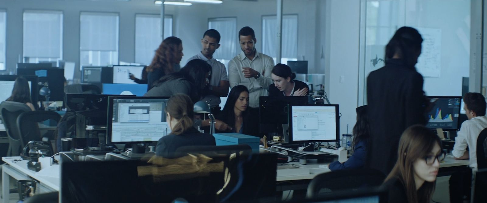 A group of people standing around a desk in an office – Image on Kive.ai
